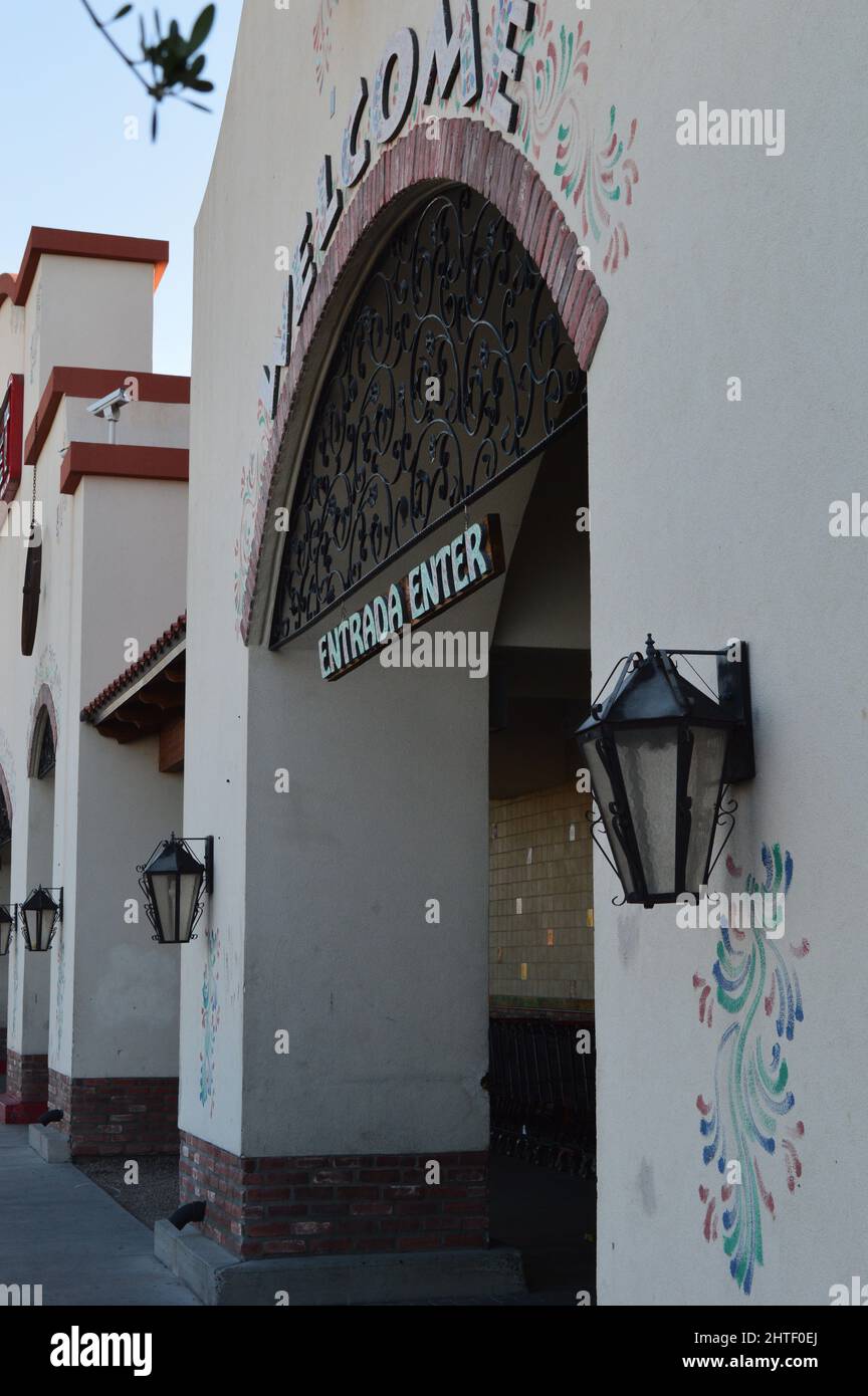Vertical shot of Enter/Entry sign hanging above a Spanish market's arch ...