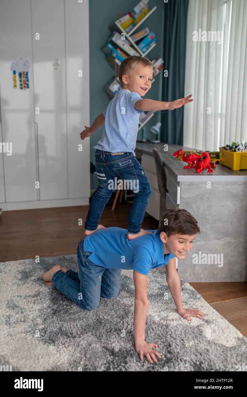 Joyful kid working out assisted by his younger sibling Stock Photo - Alamy