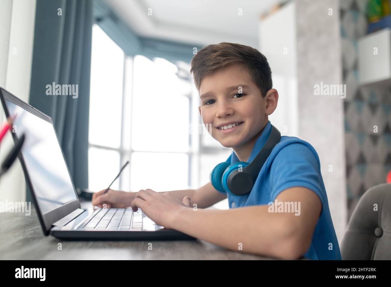 Joyous kid posing for the camera during his online lesson Stock Photo ...