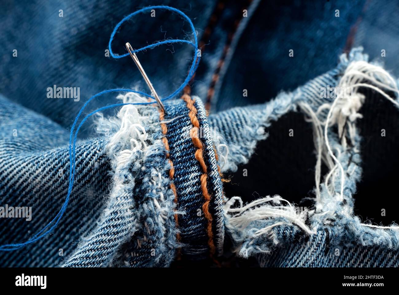 Hole in jeans. Needle with thread for darning jeans. Tools for work ...