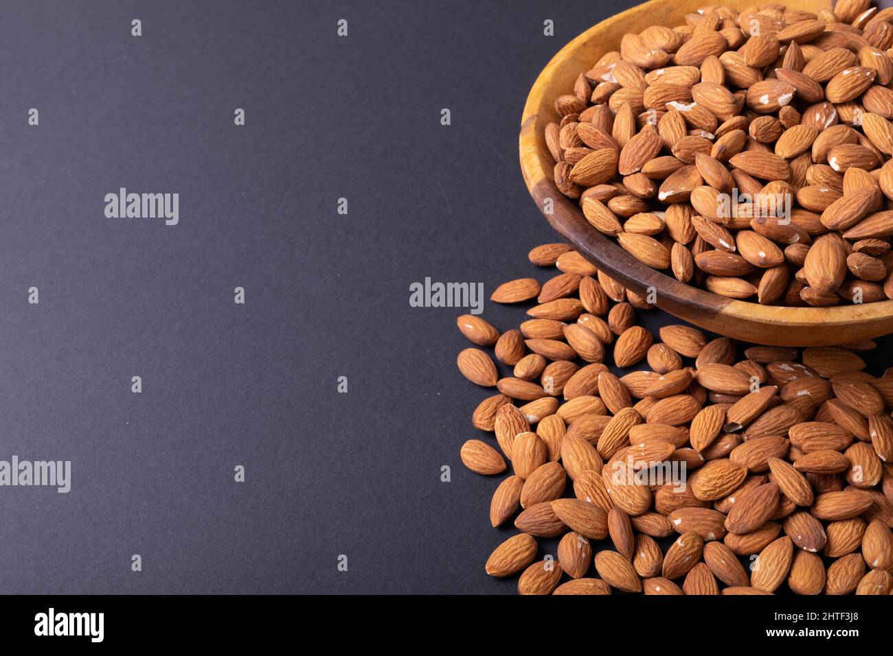 High angle view of nutritious almonds in wooden container on black ...