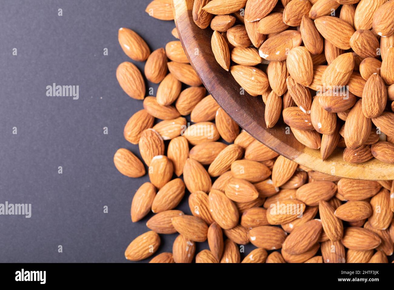 Extreme close-up of fresh almonds in wooden table on black background ...