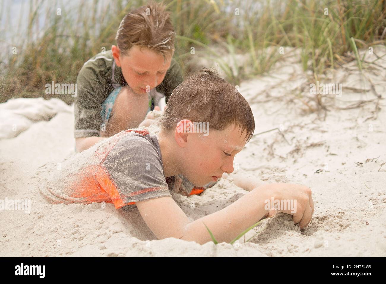 Young boys playing in the sand near sea grass Stock Photo - Alamy