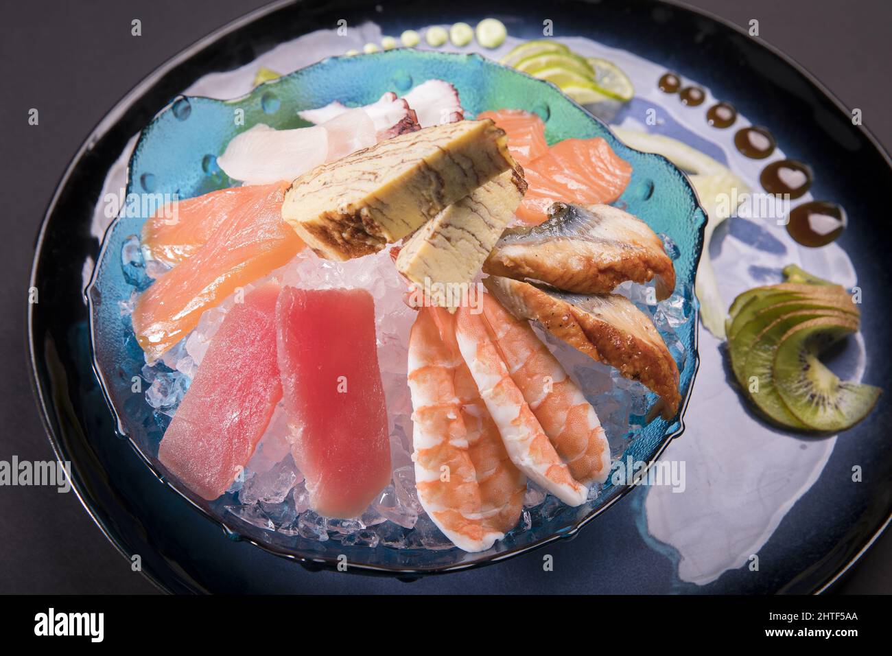 Shot of king prawns, sashimi, and salmon fillet on a blue marine glass ...