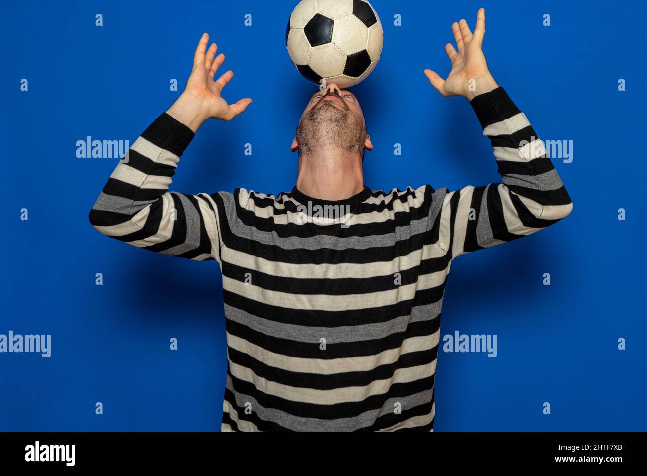 Portrait of fun cheerful young Hispanic man controlling a soccer ball ...