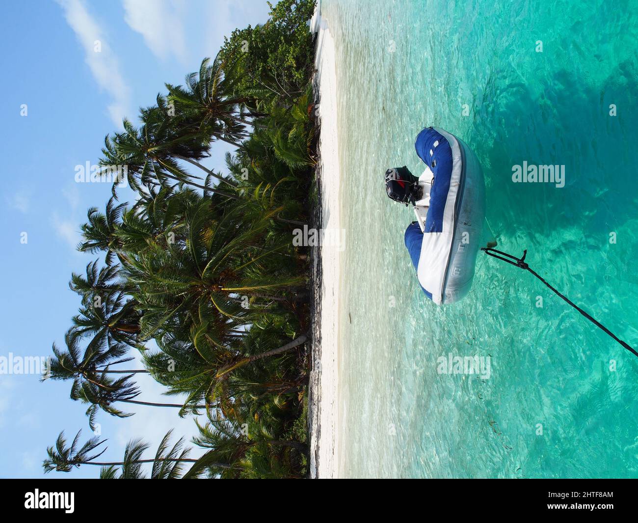 Tied to the back of boat in front of beautiful beach with clear water ...