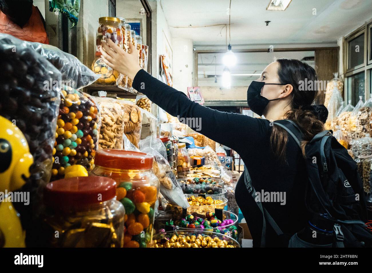 Woman at a Chinese candy store grabbing candy with a mask Stock Photo ...