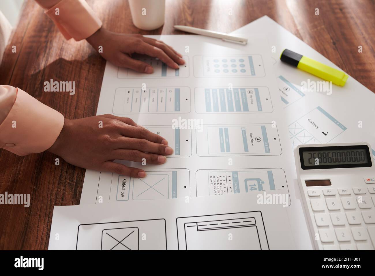 UI designer checking documents with printed mockups for mobile ...