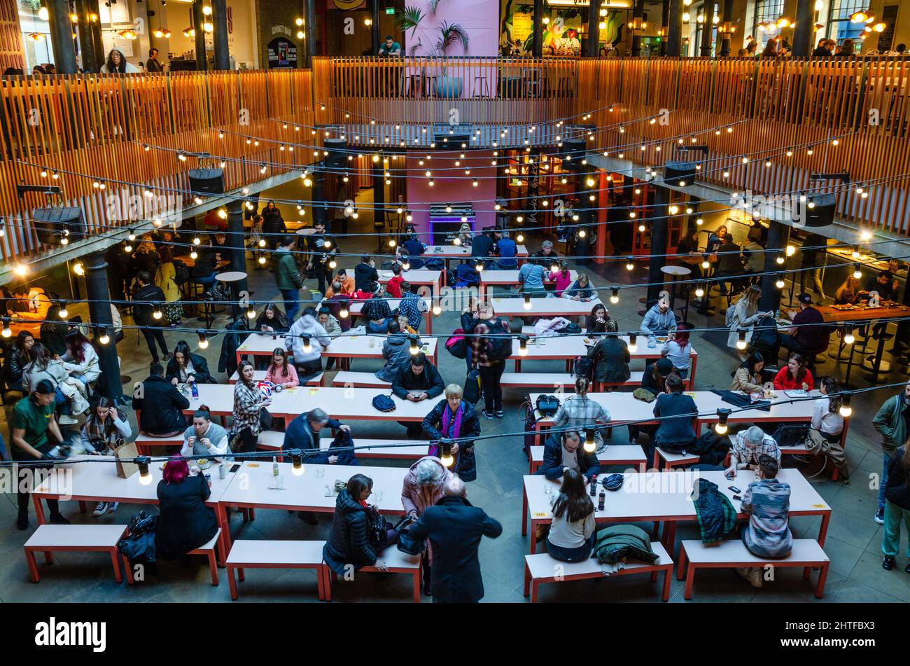 People sitting and eating at tables in a food court in the Seven Dials ...