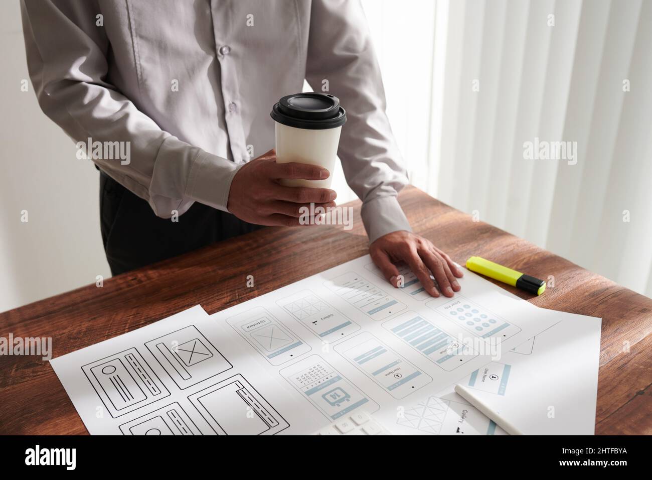Project manager drinking cup of coffee when checking mobile app ...