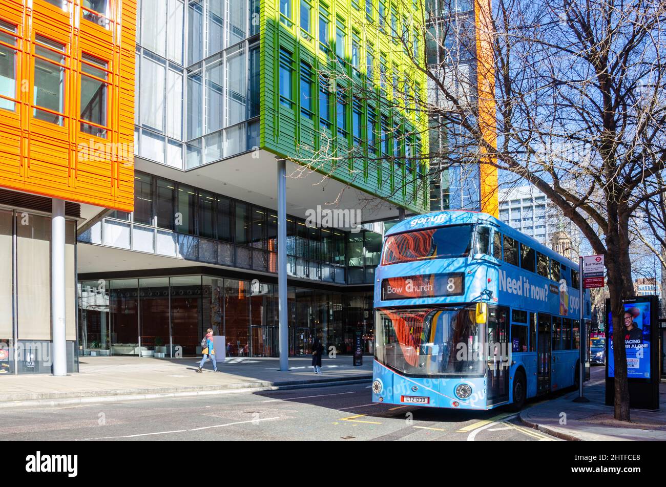 A blue bus parked at a bus stop in front of the modern office buildings ...