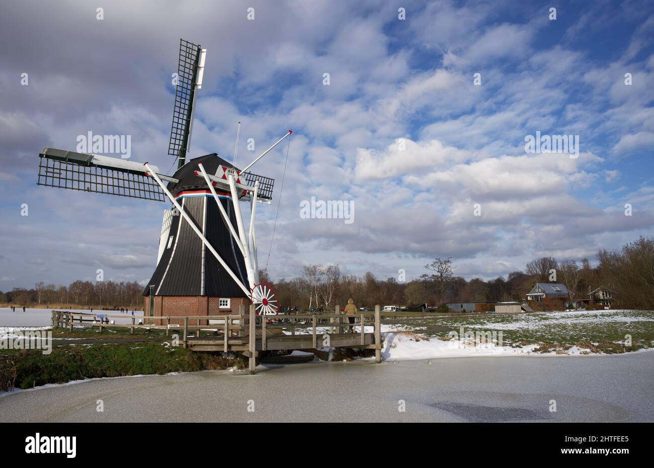Typical dutch windmill in winter with frozen water and blue sky with ...