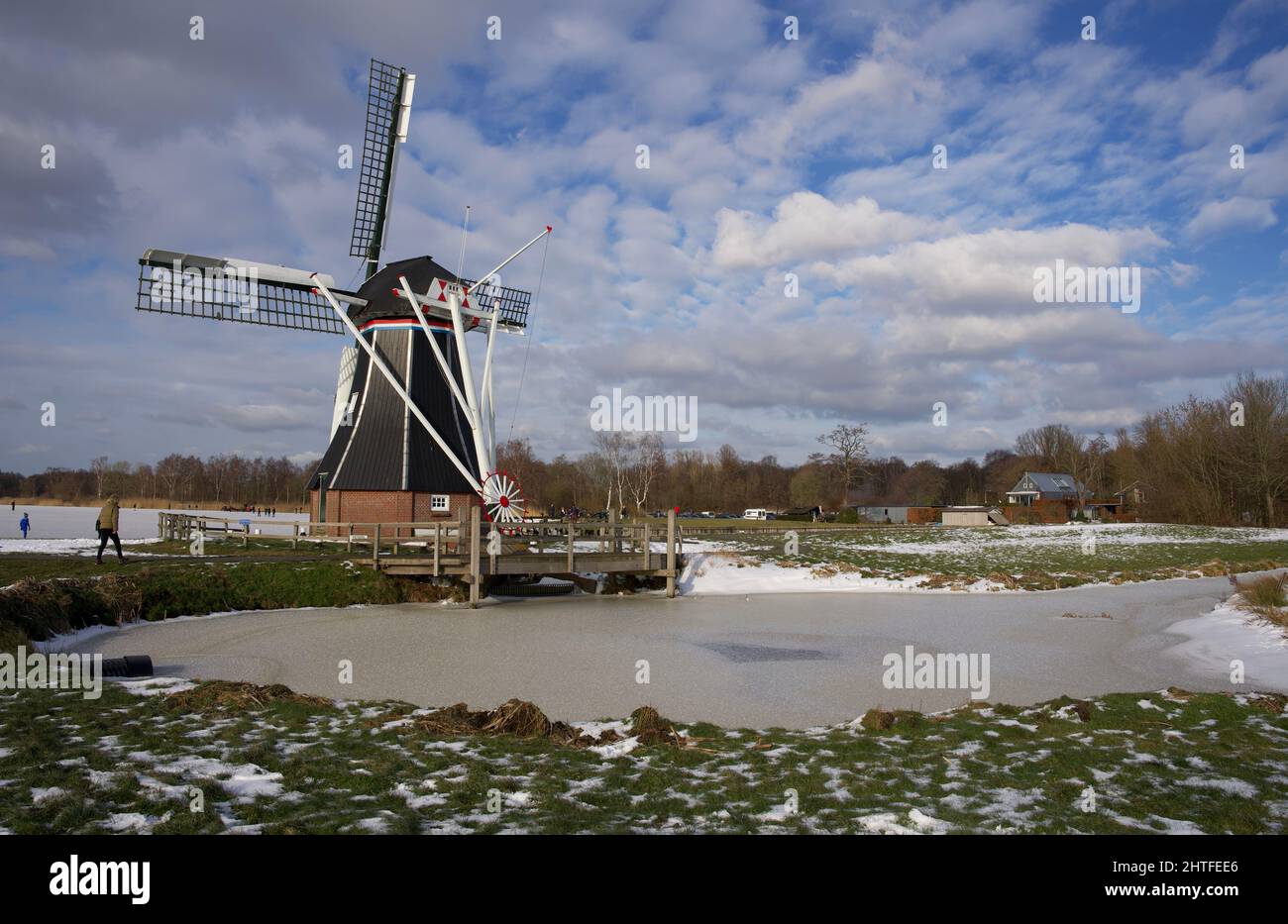 Typical dutch windmill in winter with frozen water and blue sky with ...