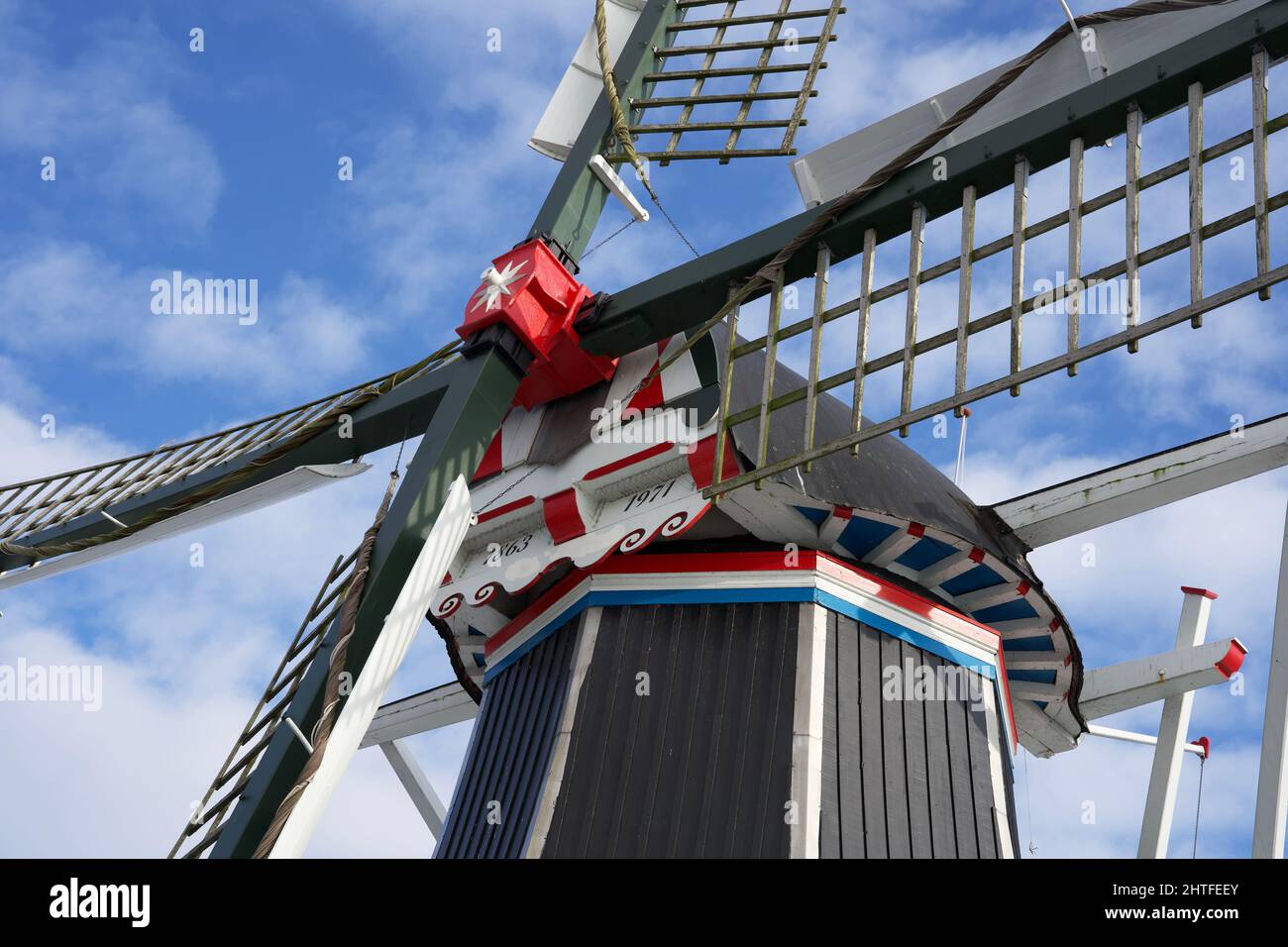 Typical dutch windmill in winter with frozen water and blue sky with ...