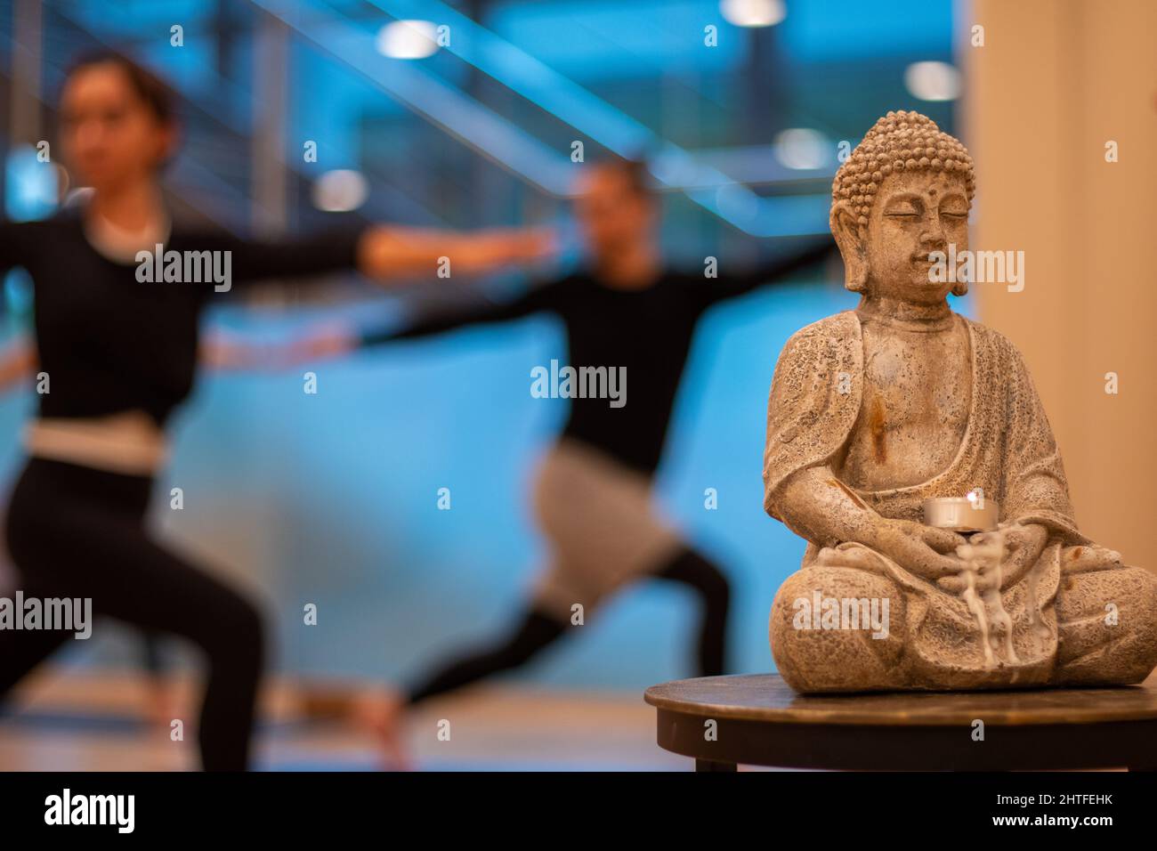 Buddha statue in front of people doing yoga Stock Photo - Alamy