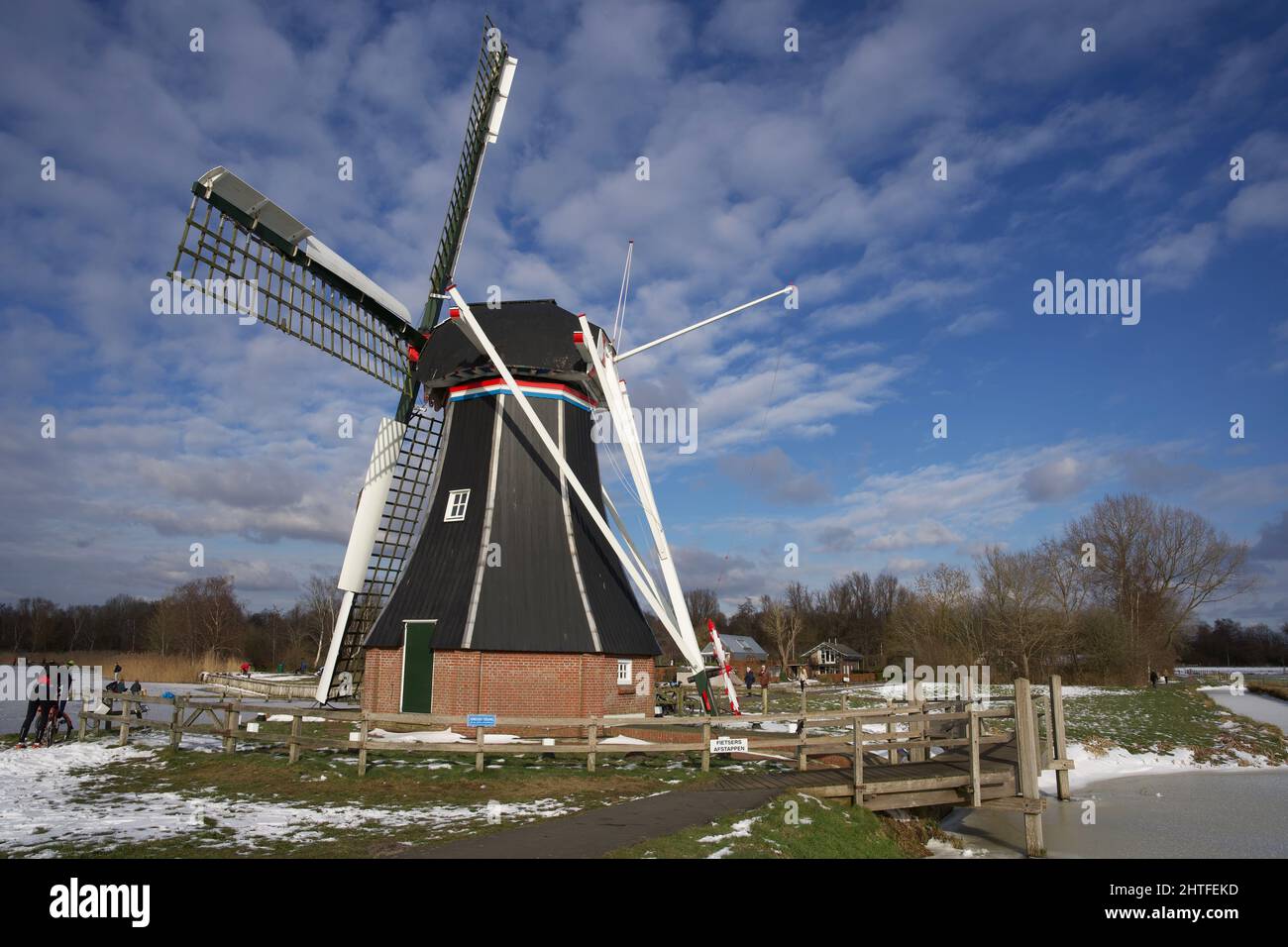 Typical dutch windmill in winter with frozen water and blue sky with ...