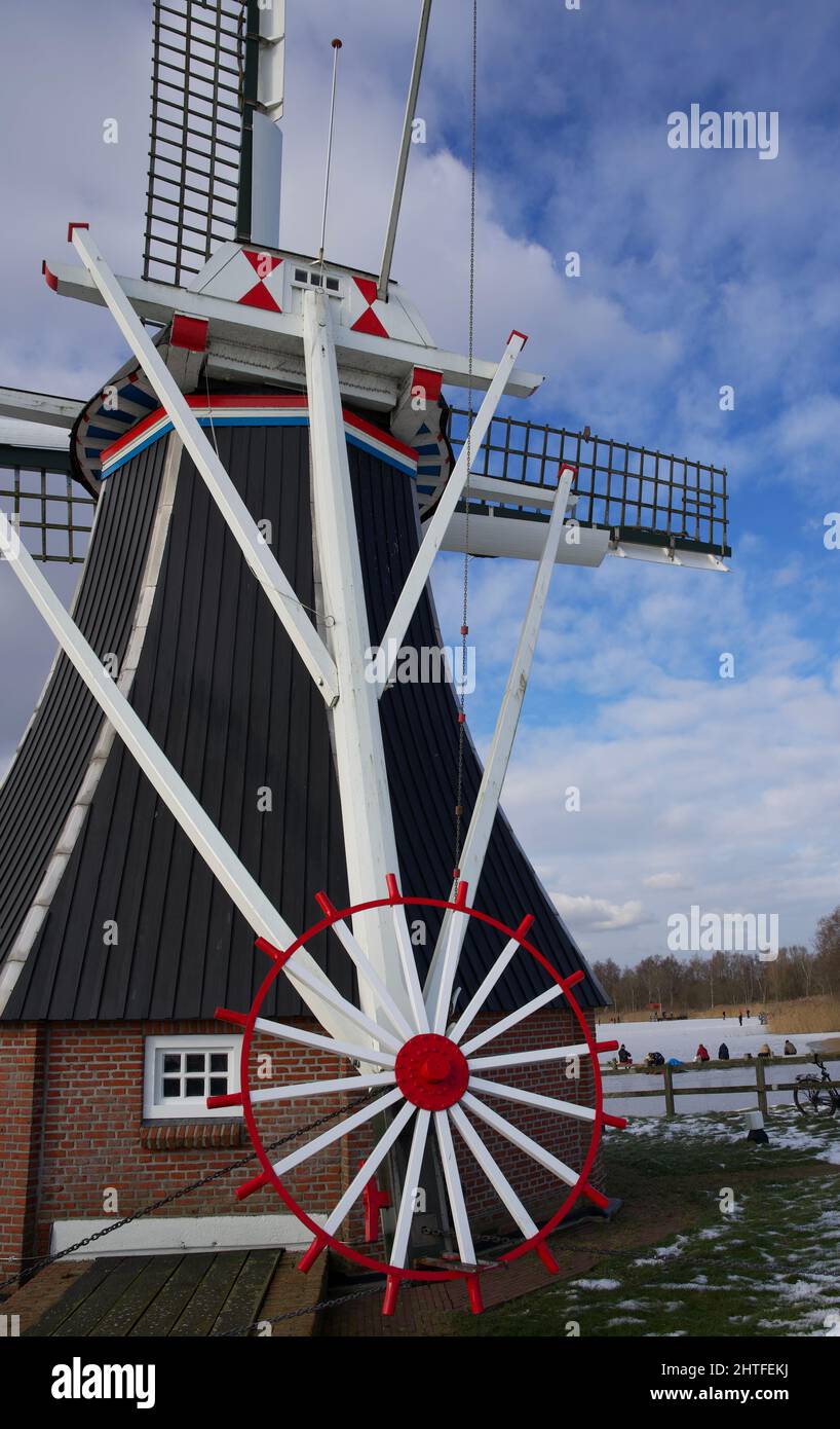 Typical dutch windmill in winter with frozen water and blue sky with ...