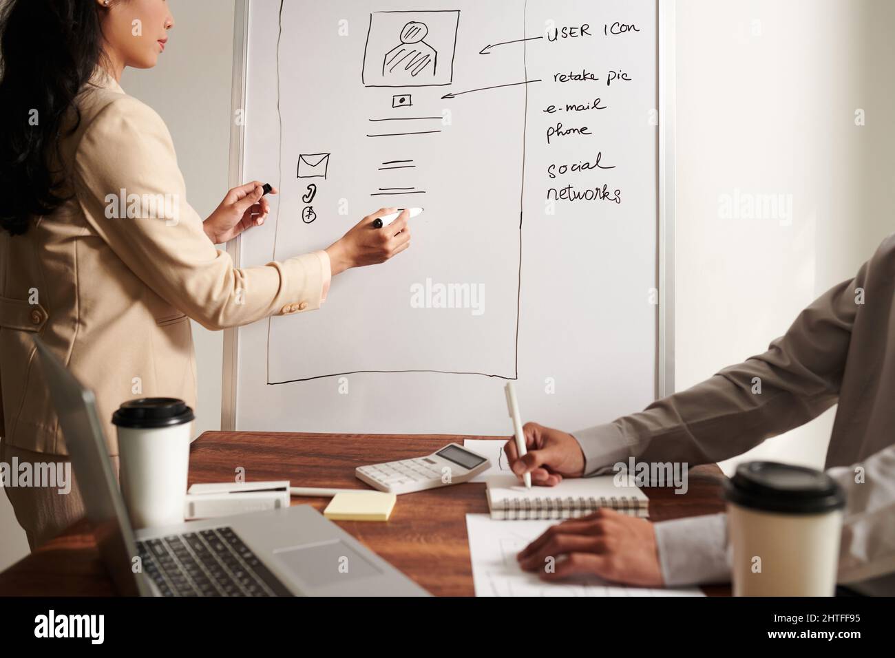 Female UX designer drawing and writing her ideas on whiteboard when ...