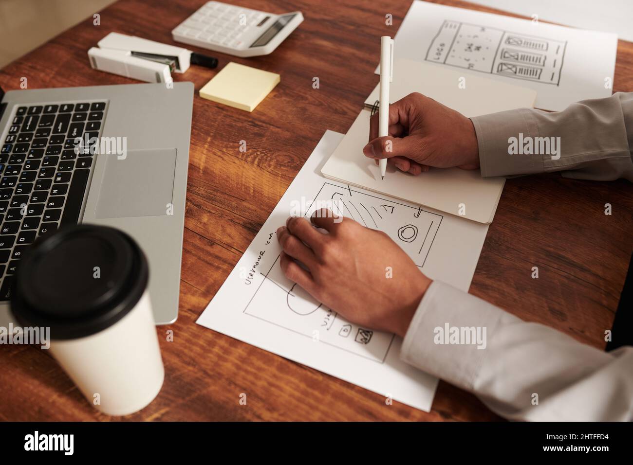 Hands of UI designer drawing wireframes for pages of website or mobile ...