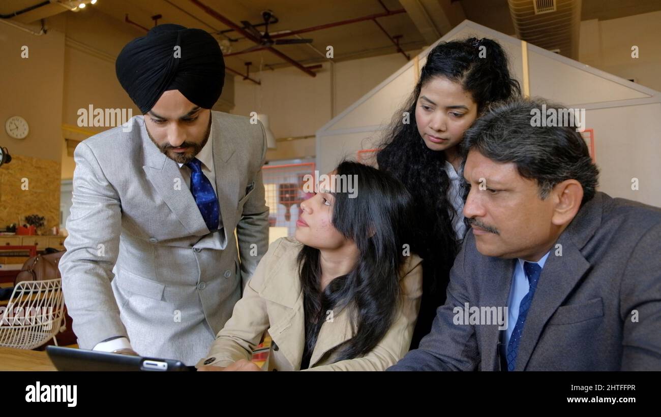 Corporate team of South Asians from India working together looking at a ...