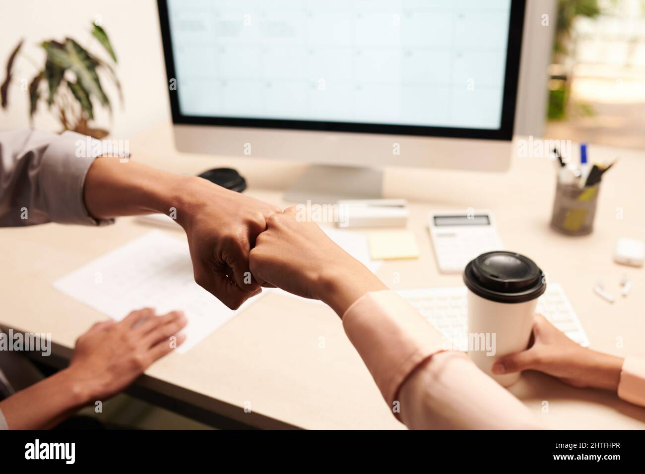 Business people giving each other fist bump to celebrate finishing work ...