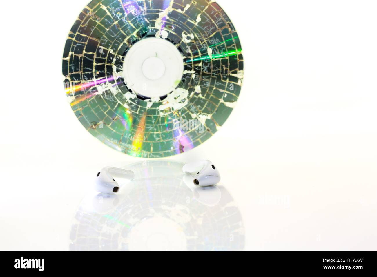 Destroyed cd with Wi-Fi earphones on a white surface and background ...