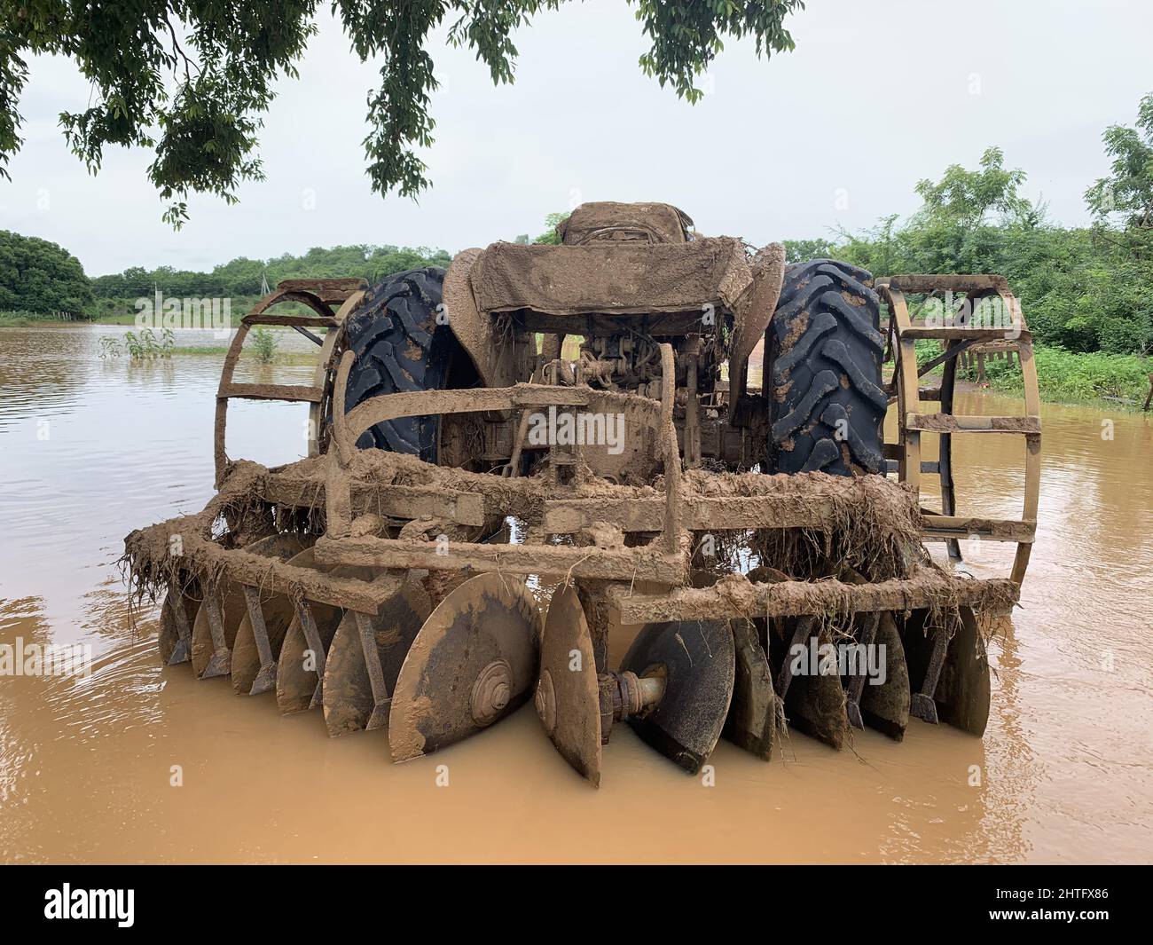 Tractor in the mud under green tree Stock Photo - Alamy