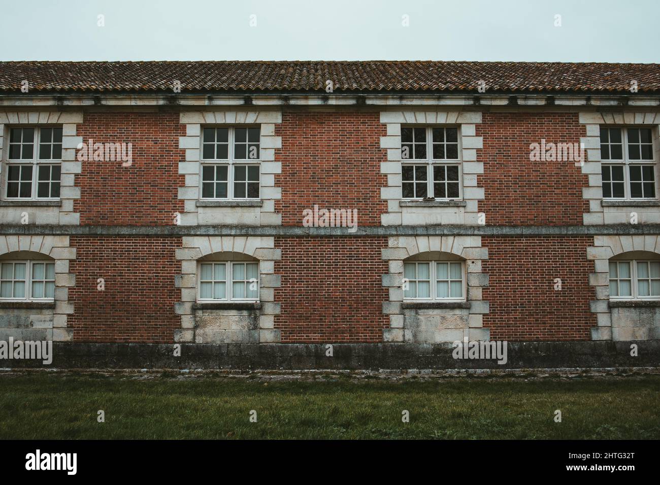 Beautiful exterior view of an old red stone building with white windows ...