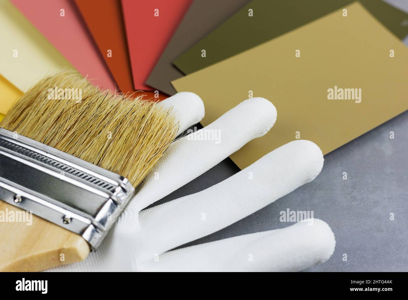 A brush with a wooden handle and paint samples on a gray background ...
