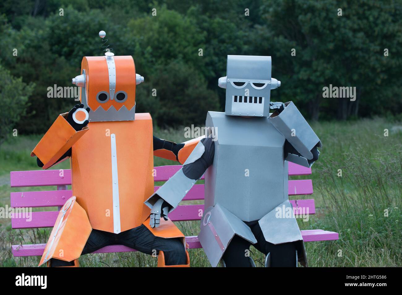 Colorful robots sitting on bench, socializing, talking, connecting and ...
