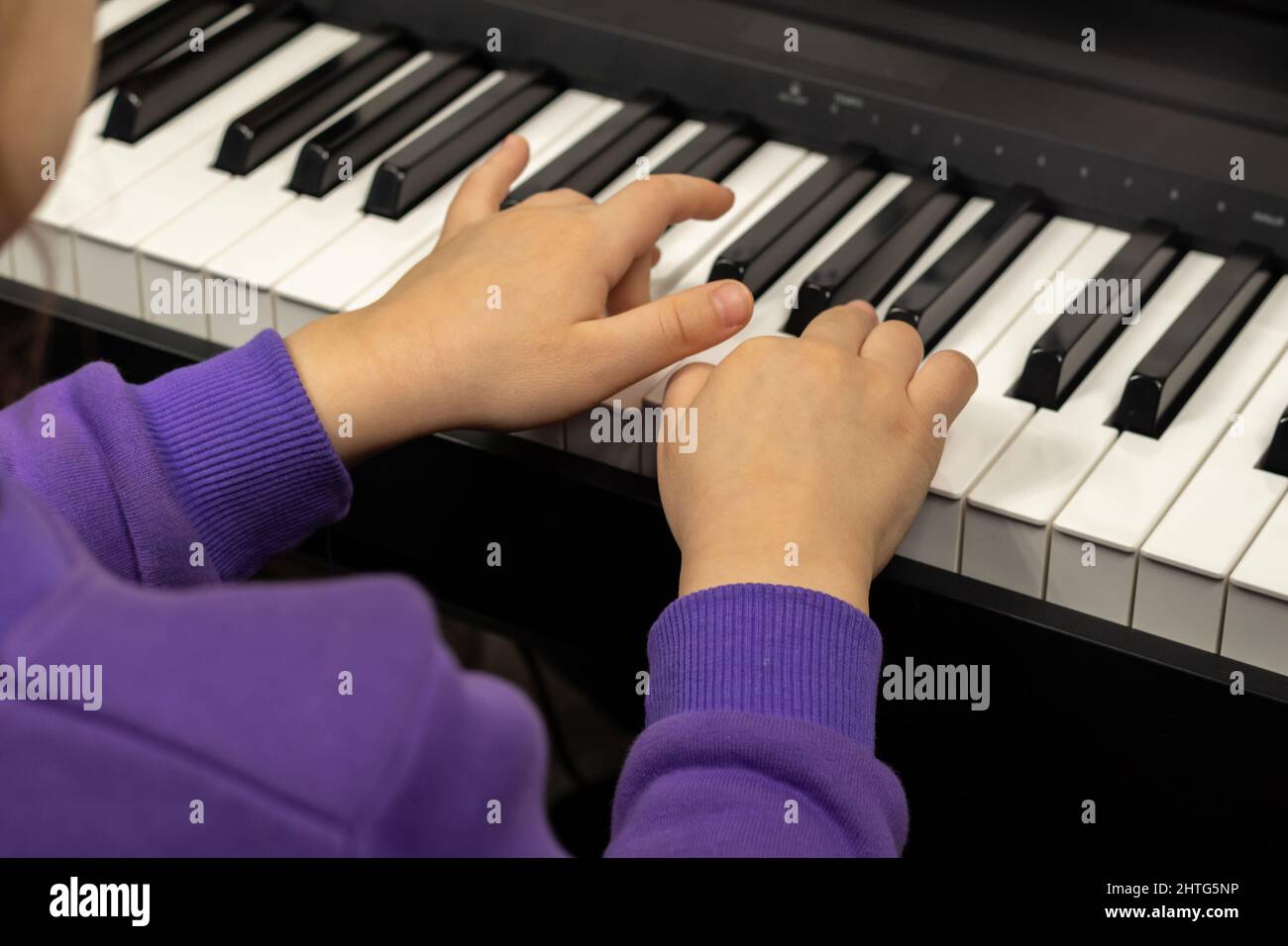 Two hands of a child playing the piano. Selective focus on children's ...