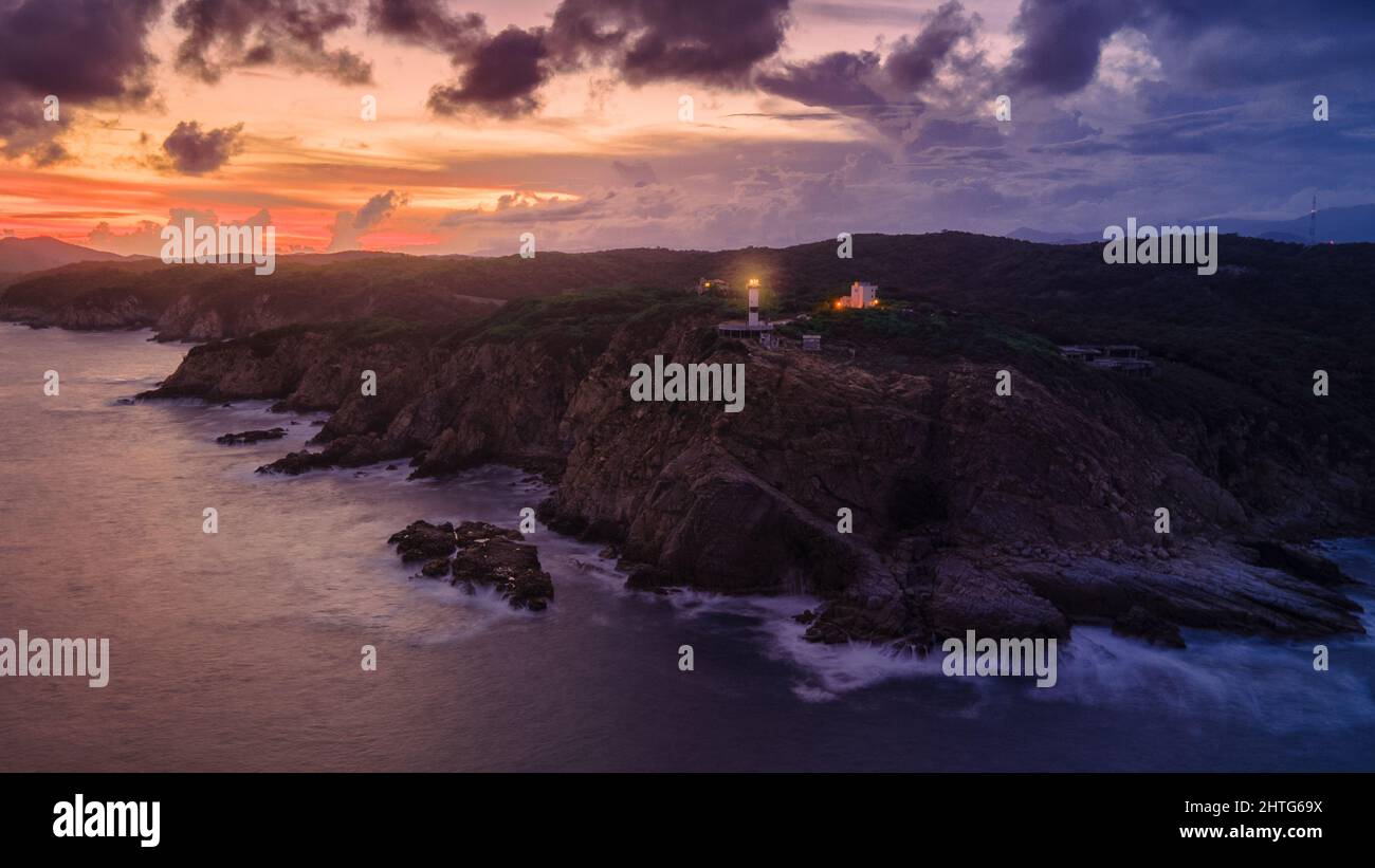 Aerial shot of sea waves breaking on a rocky coastline and a lighthouse ...