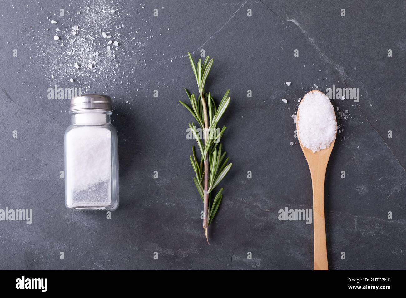 Overhead view of salt shaker with rosemary and wooden spoon arranged ...