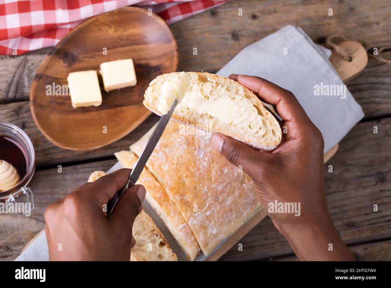 Cropped hands of african american man applying butter on bread slice ...