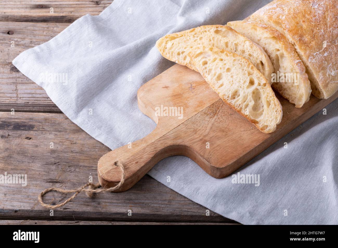 High angle view of bread slices on wooden serving board over napkin at ...