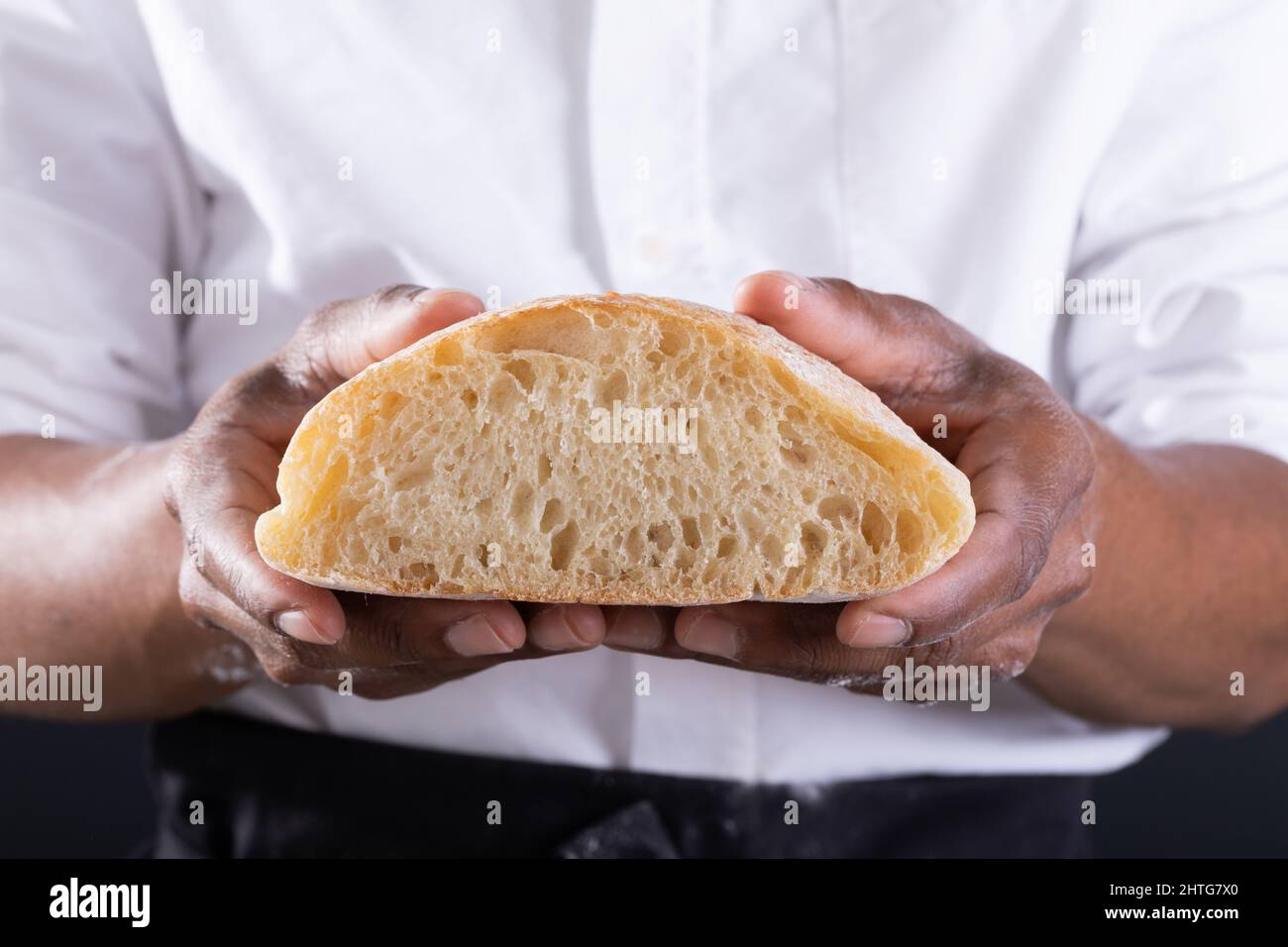 Close-up midsection of african american male baker showing cross ...