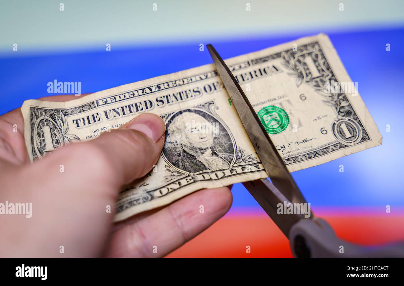 hand with scissors cutting a dollar bill with the russian flag in the ...