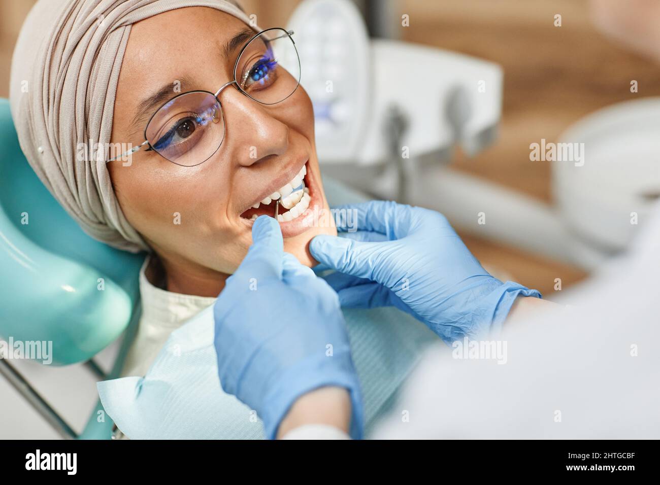 Close up of young Middle-Eastern woman in dental chair with mouth open ...