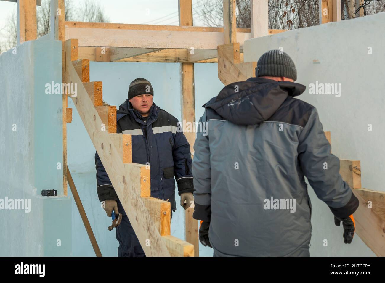 Two workers assemble the slide frame from wooden beams Stock Photo - Alamy