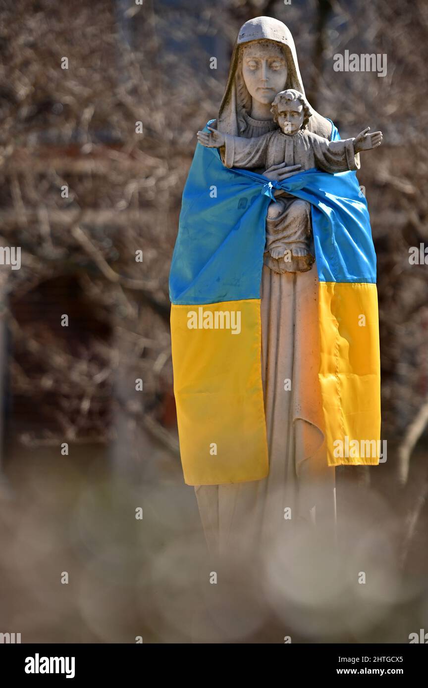 The flag of Ukraine has been tied around a statue of the Virgin Mary ...