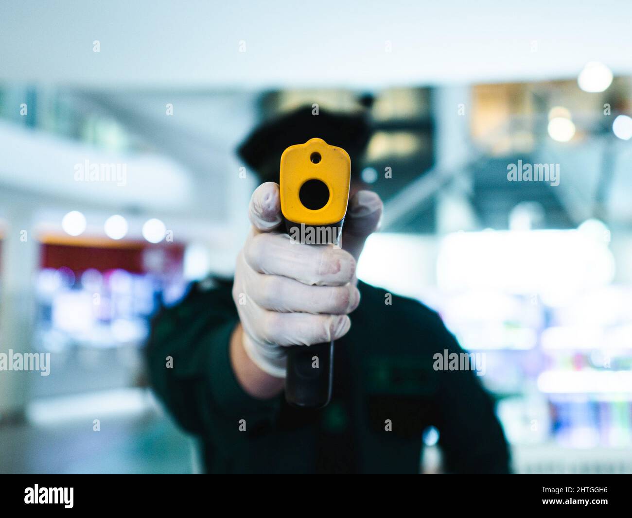 Closeup shot of a man pointing a gun-like thermometer at the camera ...