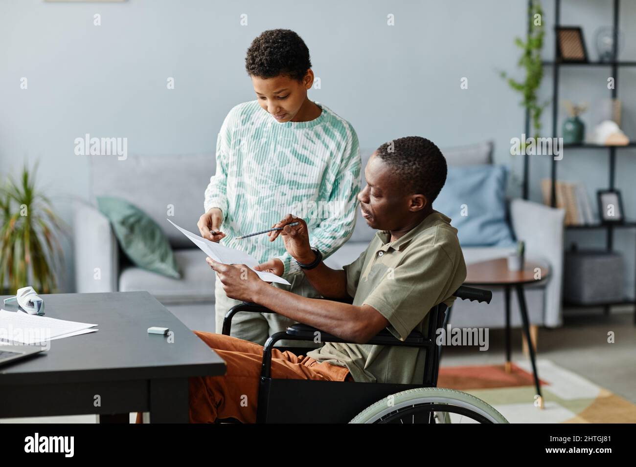 Side view portrait of African American man in wheelchair helping ...