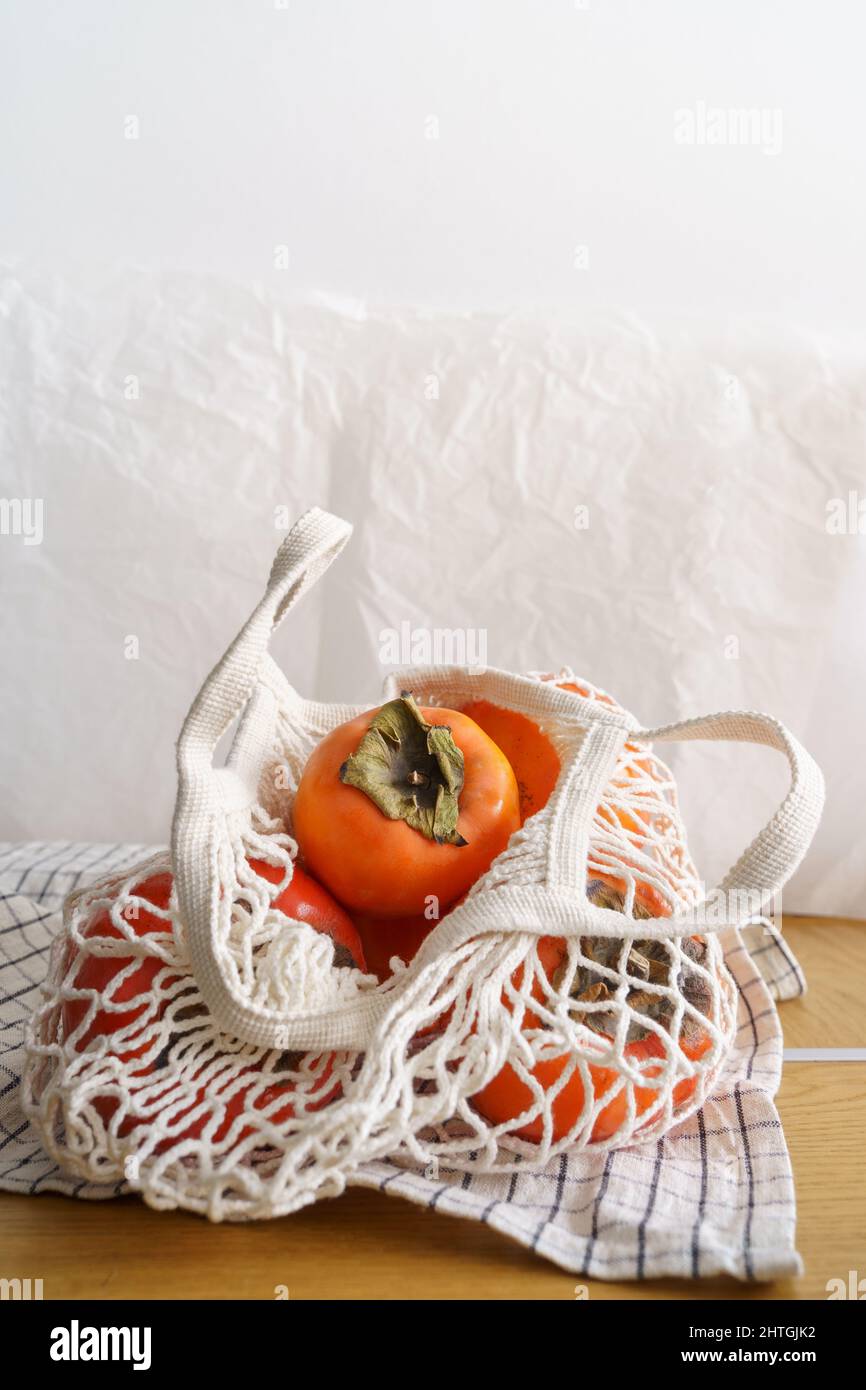 Front view orange persimmon in string bag natural light Stock Photo - Alamy
