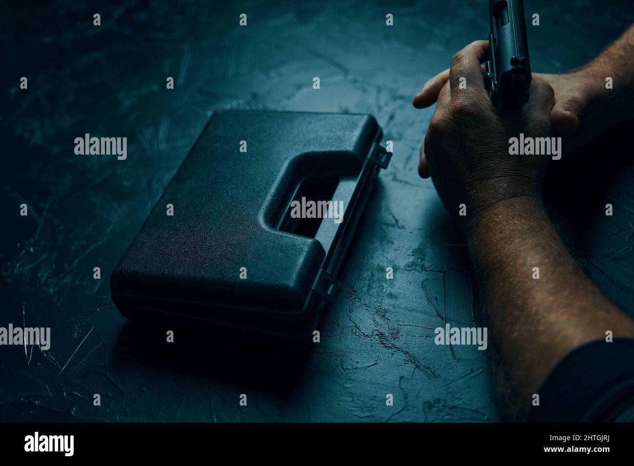 Hands with weapon and suitcase from under gun on concrete table Stock ...