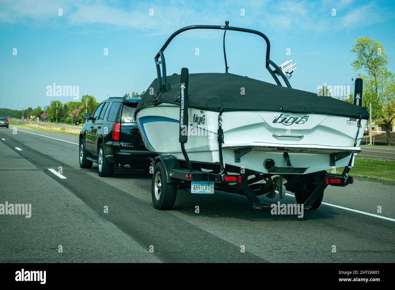 Black Tahoe Car pulling a white inboard speedboat on the highway ...