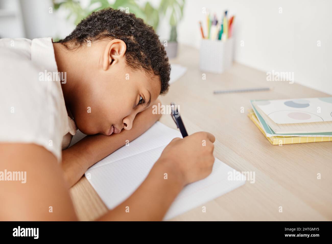 Portrait of sad and bored child laying head on desk while struggling ...