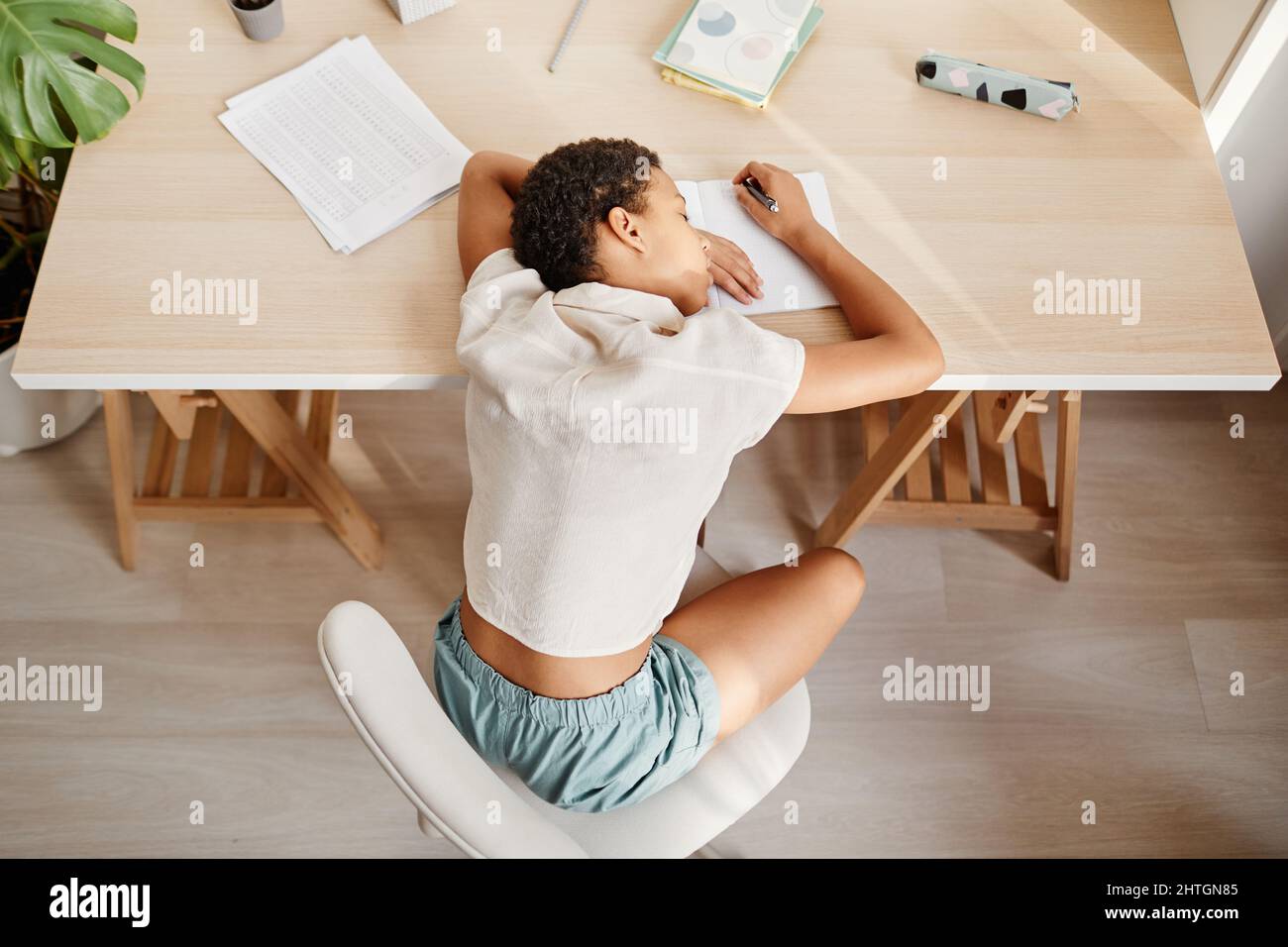 Top view of sleeping African American girl laying head on desk while ...