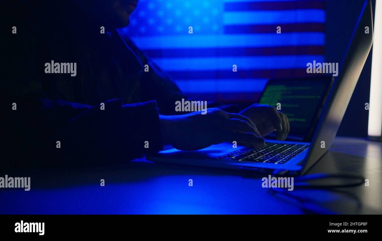 Hacker with laptop and USA flag in background. Cyber attack concept ...