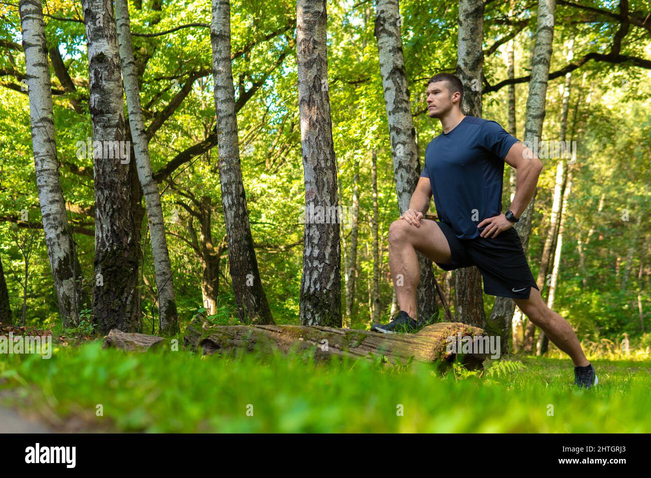 A young enduring athletic athlete is doing stretching in the forest ...