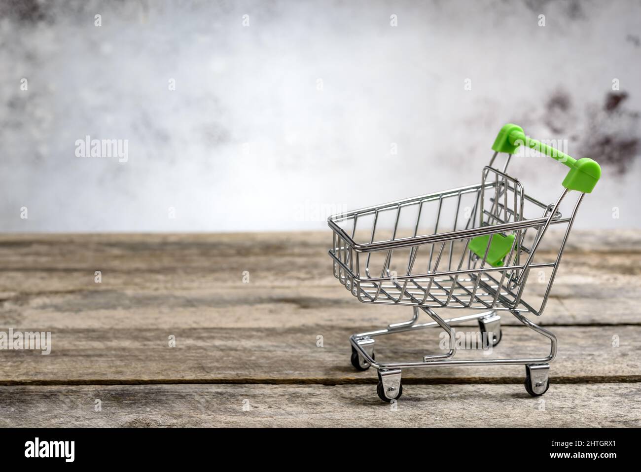 Empty mini metal shopping cart with wheels on a rustic wooden table ...